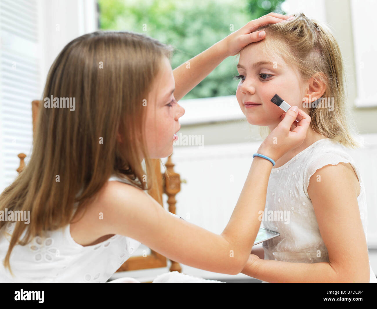 Girl putting make-up on friend Stock Photo - Alamy