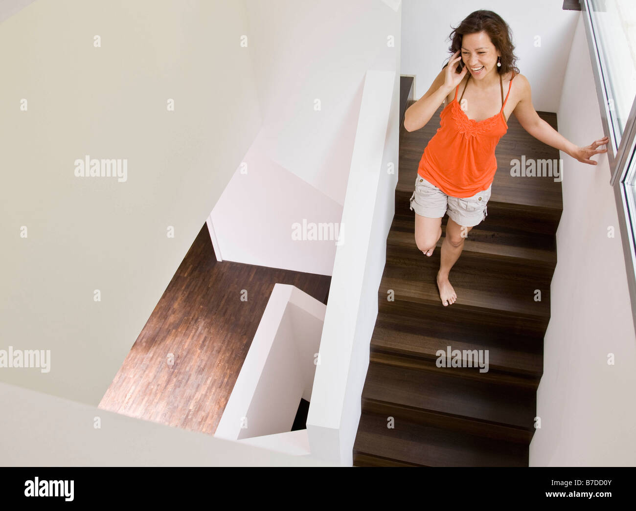 Woman walking downstairs while on phone Stock Photo - Alamy