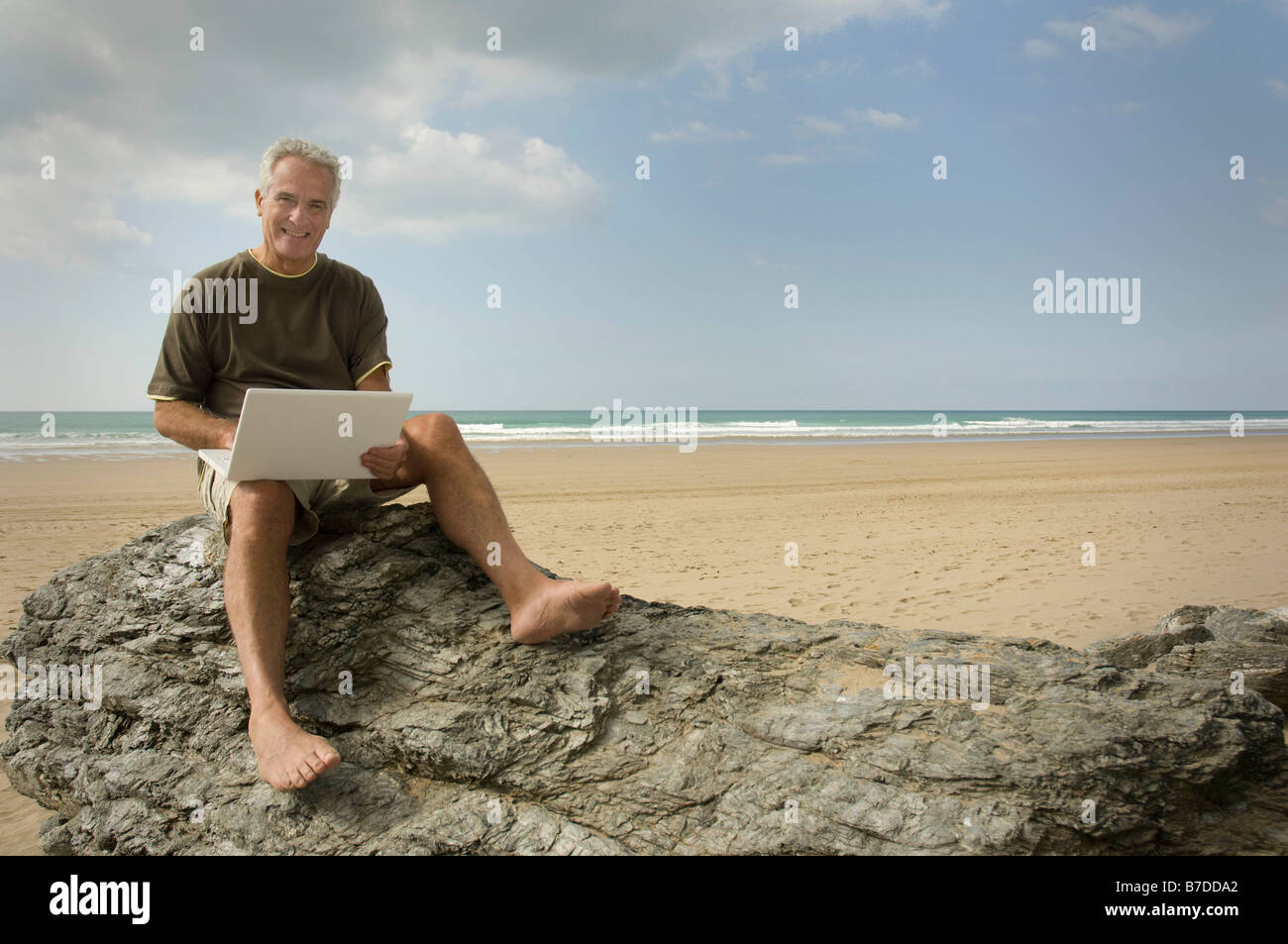 Male on a beach using his computer Stock Photo - Alamy