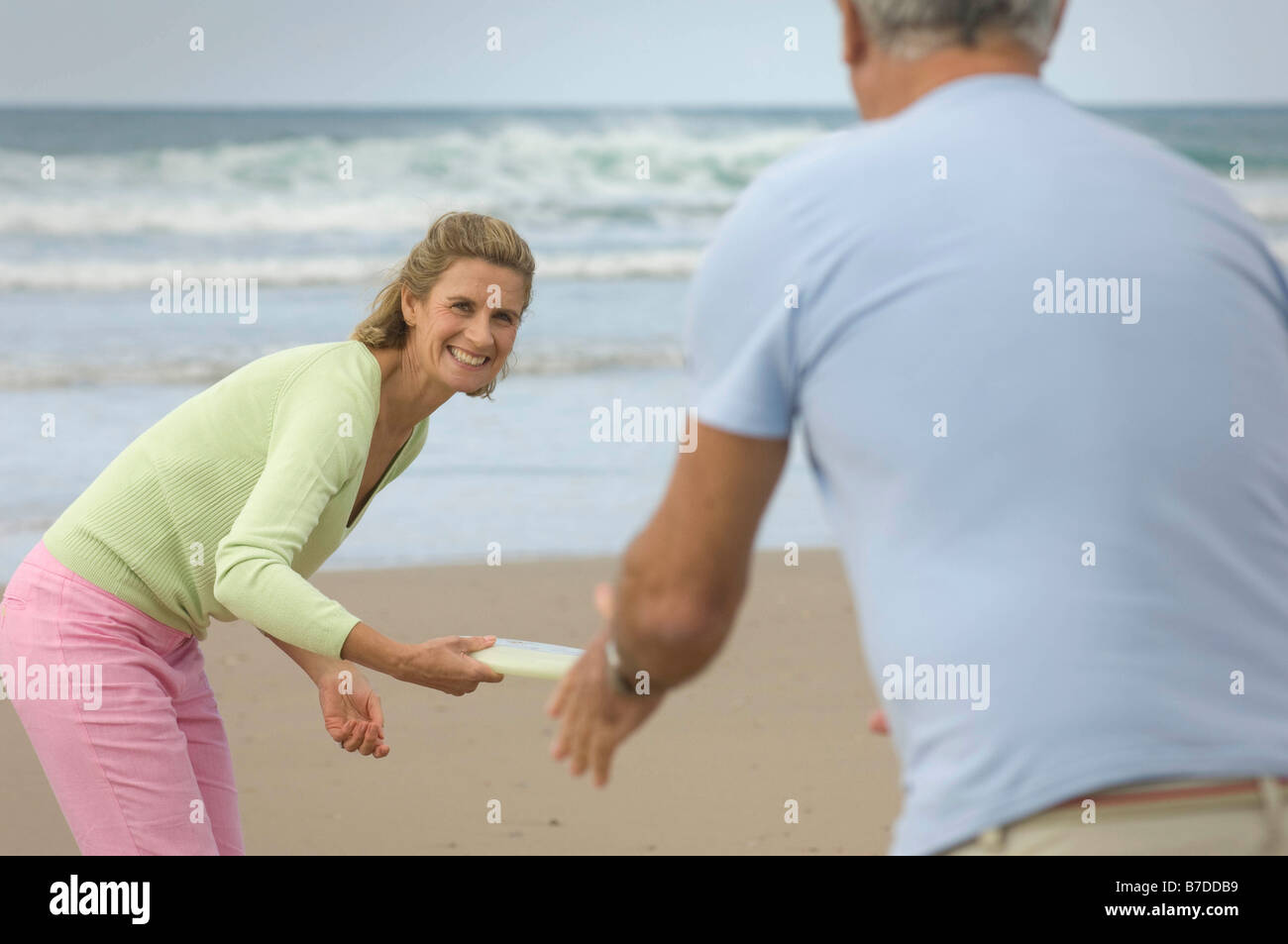 Couple playing frisbee on a beach Stock Photo - Alamy
