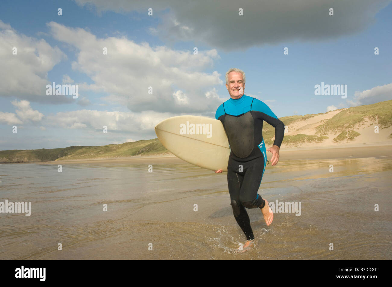 Male running into sea with a surfboard Stock Photo - Alamy