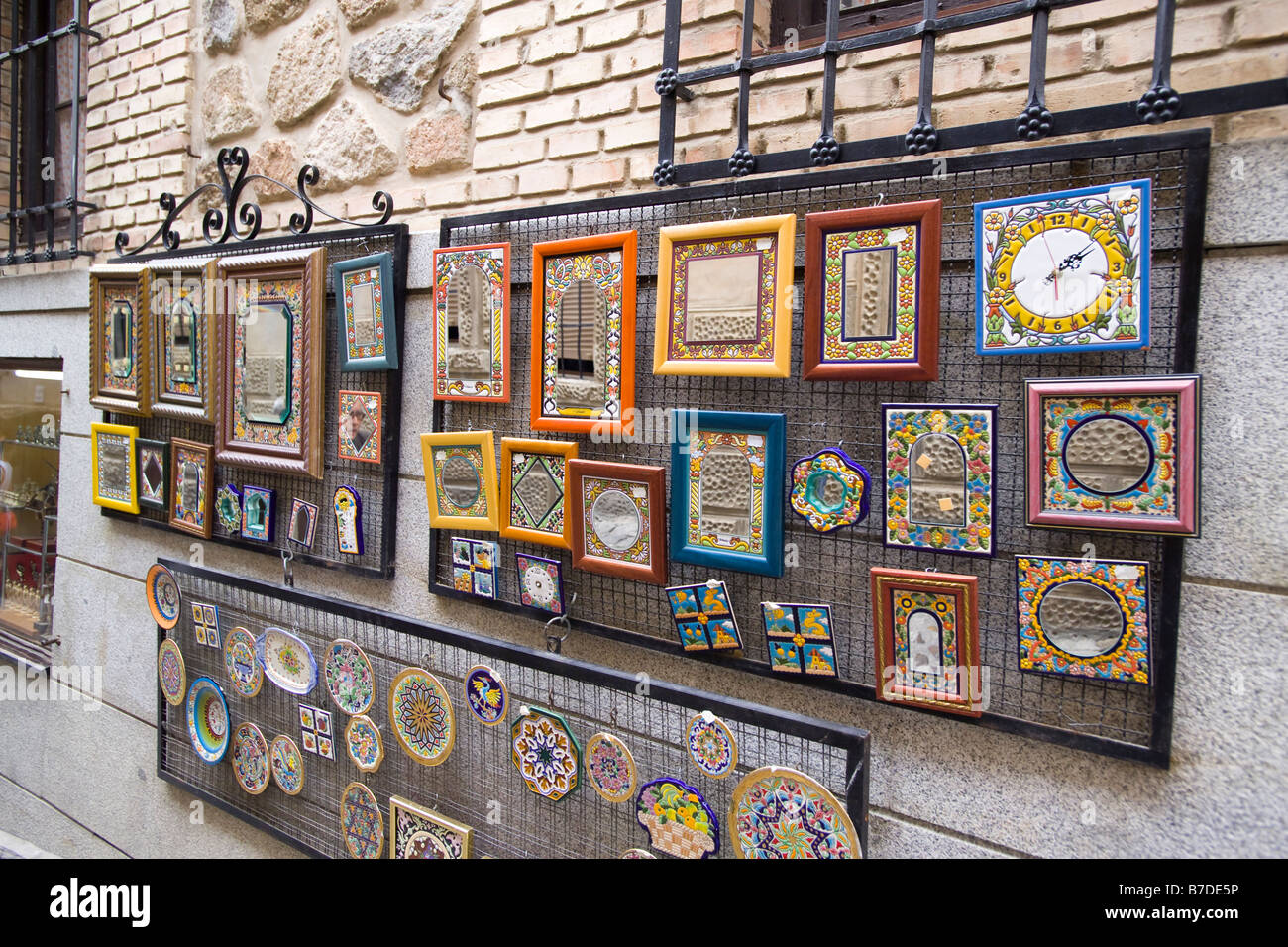 Spanish ceramic mirrors clocks and plates hang on display on a wall ...