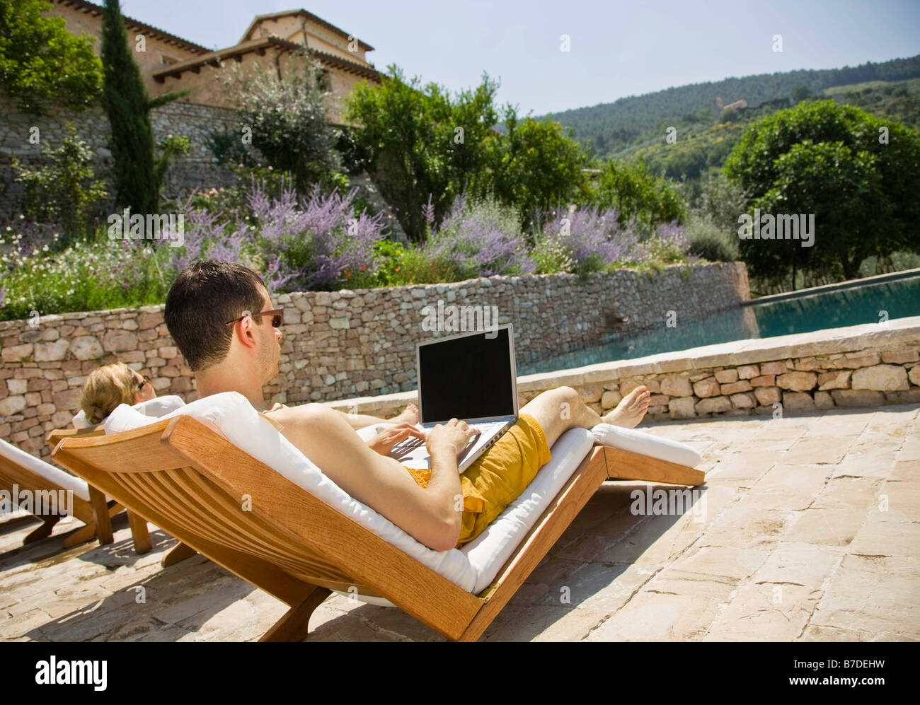 Man working on computer by the pool Stock Photo - Alamy