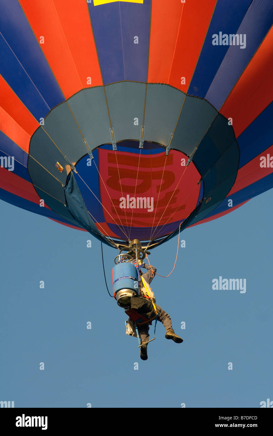 Pilot in a cloudhopper hot air balloon flying in a bright blue sky ...