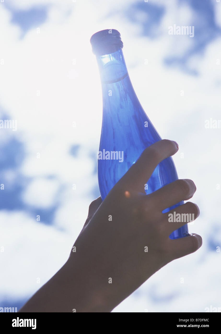Hand grabbing blue bottle Stock Photo - Alamy