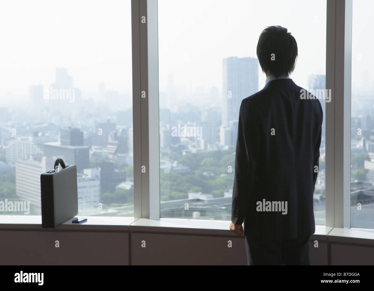 Businessman standing window looking distance hi-res stock photography ...