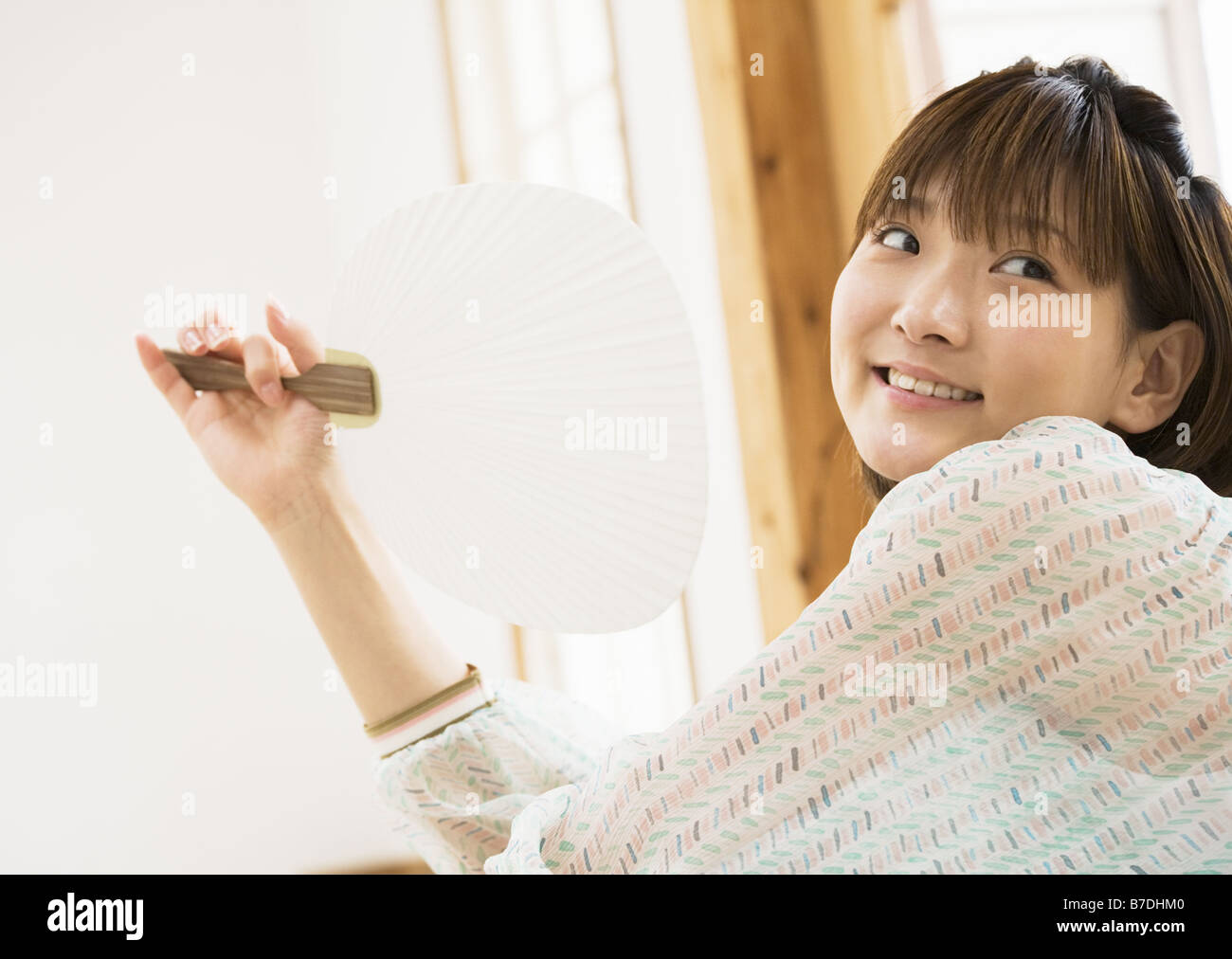 A woman waving a paper fan Stock Photo - Alamy