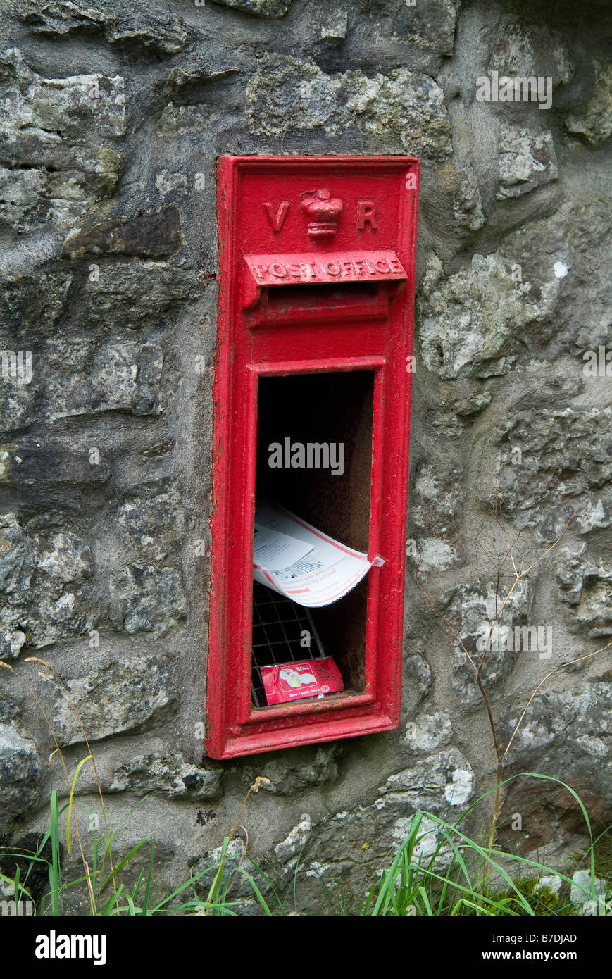 A broken disused Royal Mail post box set in a traditional stone wall ...