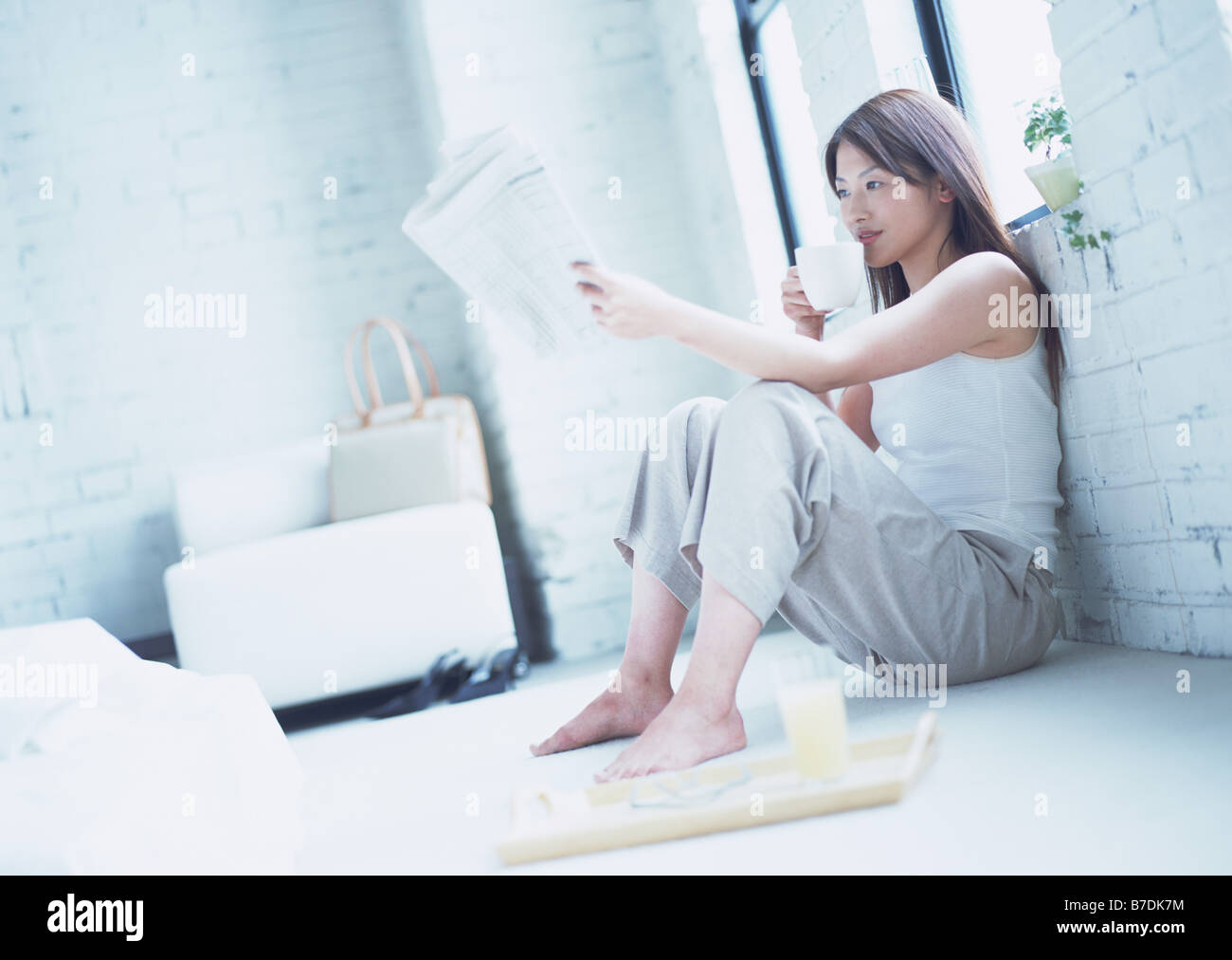 Woman reading newspaper on floor Stock Photo - Alamy