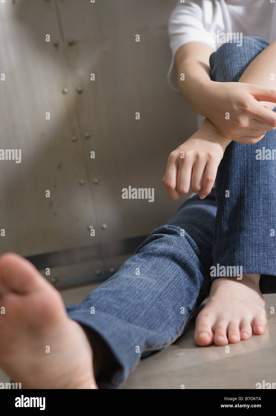 Woman sitting with arms around knee Stock Photo - Alamy