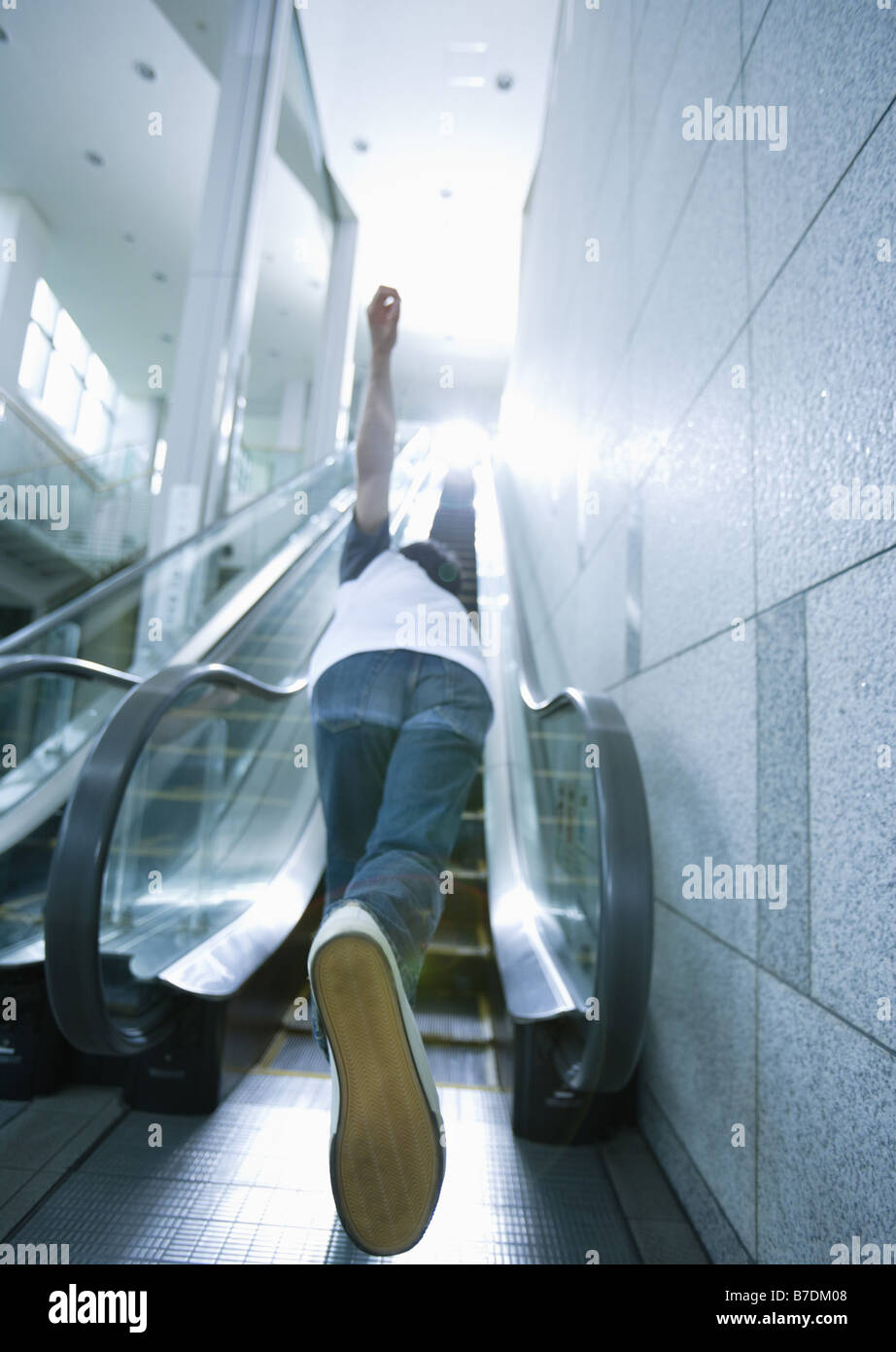 Young man running up escalator Stock Photo - Alamy