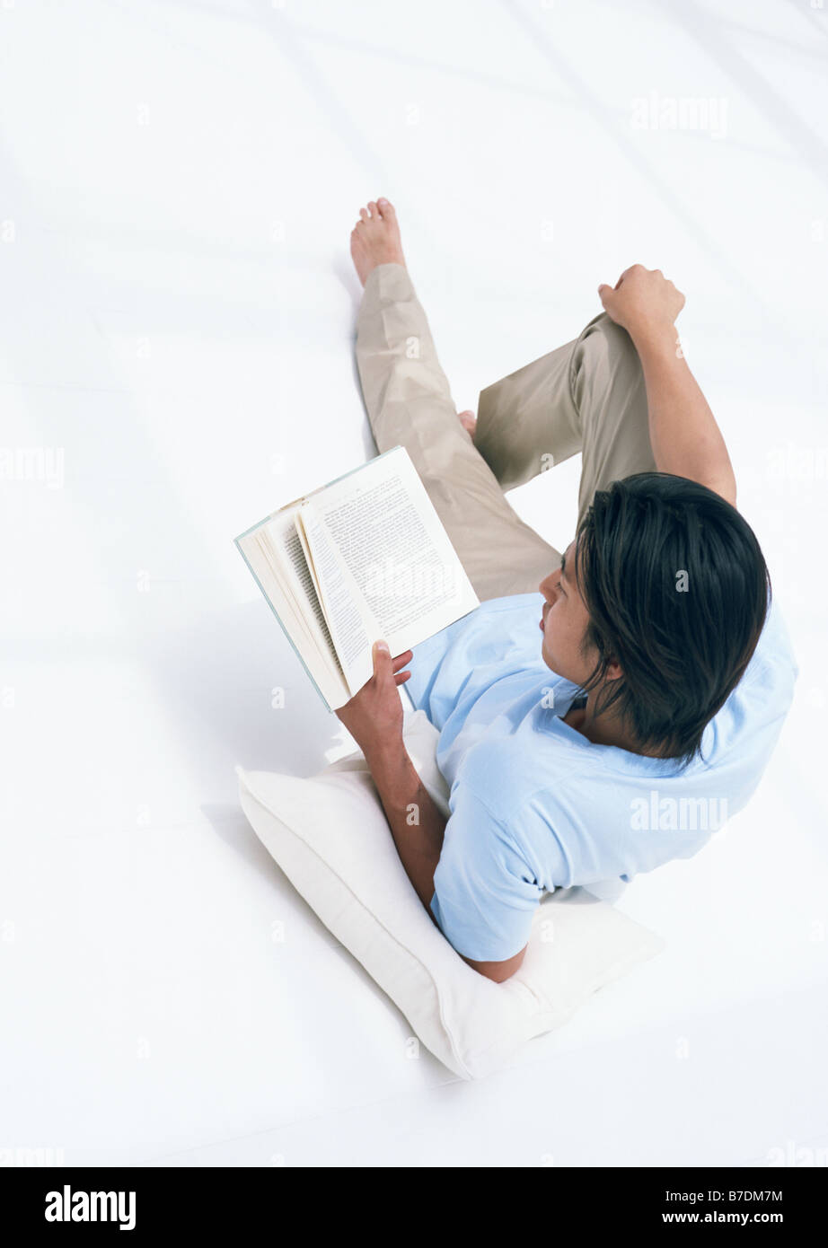 Relaxed man reading book on floor Stock Photo - Alamy