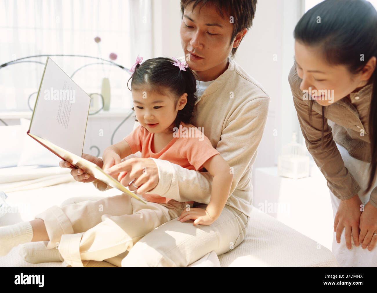 Parents and child reading a picture book Stock Photo - Alamy