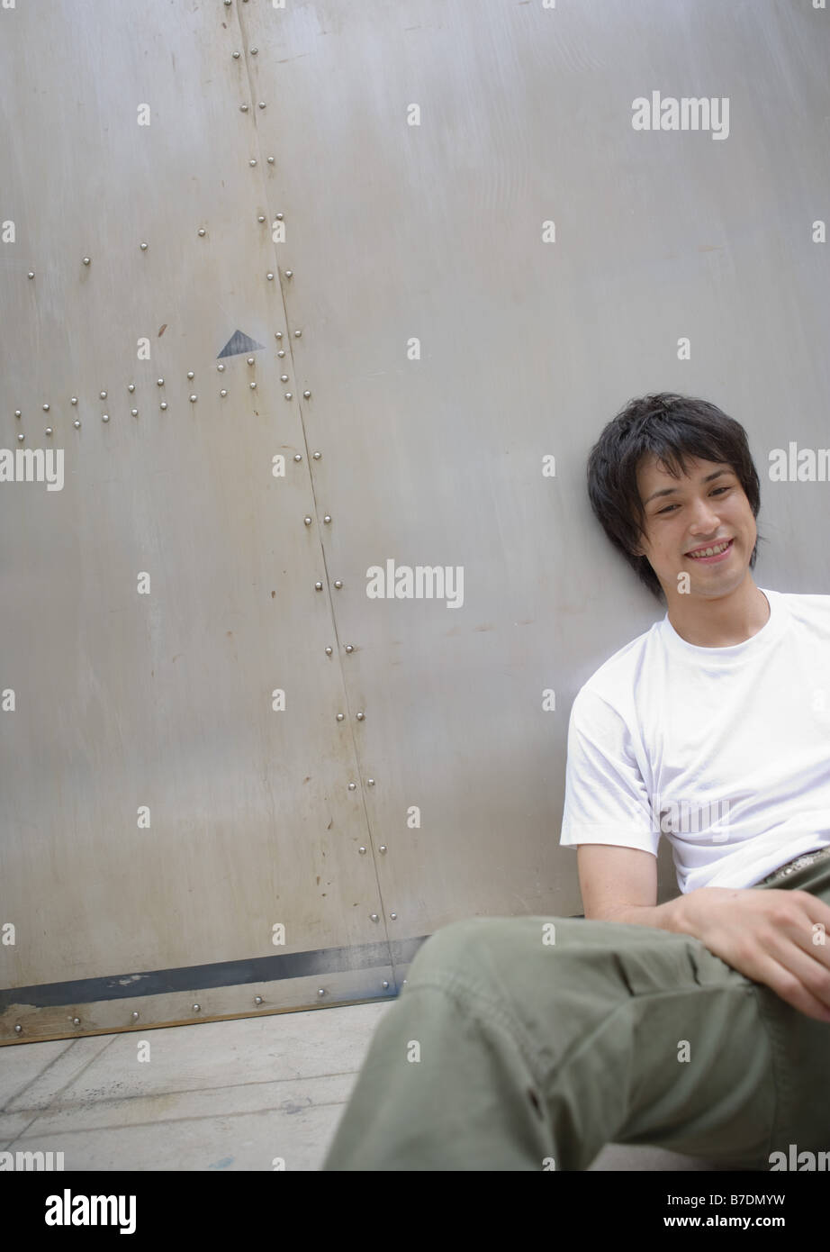 Man sitting by wall Stock Photo - Alamy