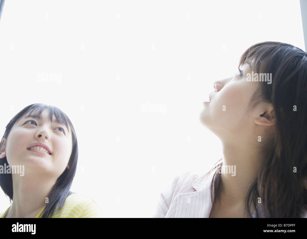 Smiling two young women looking up Stock Photo - Alamy