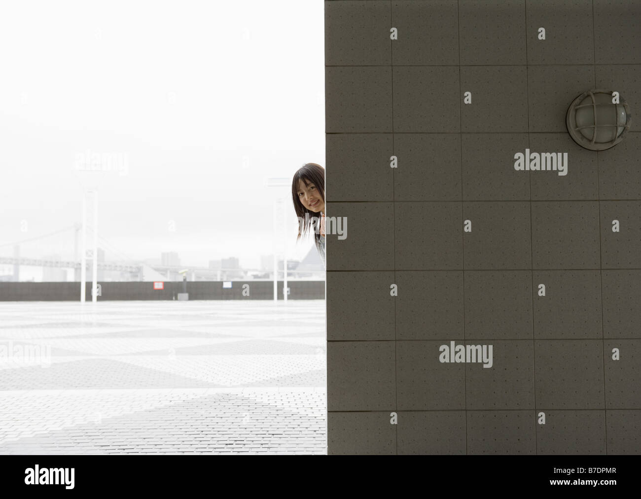 Girl peeking out from behind wall Stock Photo - Alamy