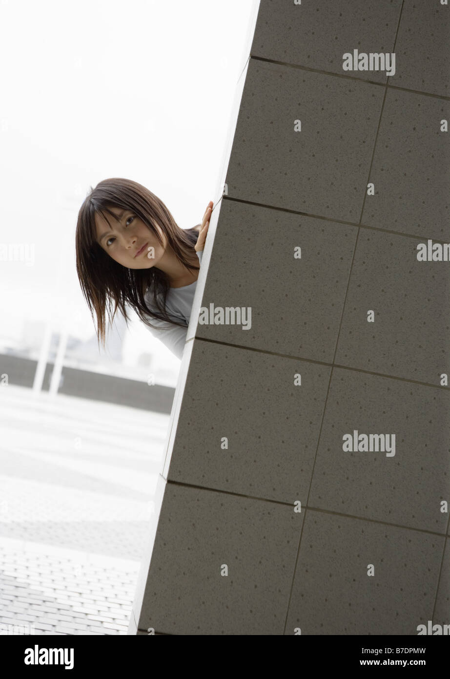 Girl peeking out from behind wall Stock Photo - Alamy