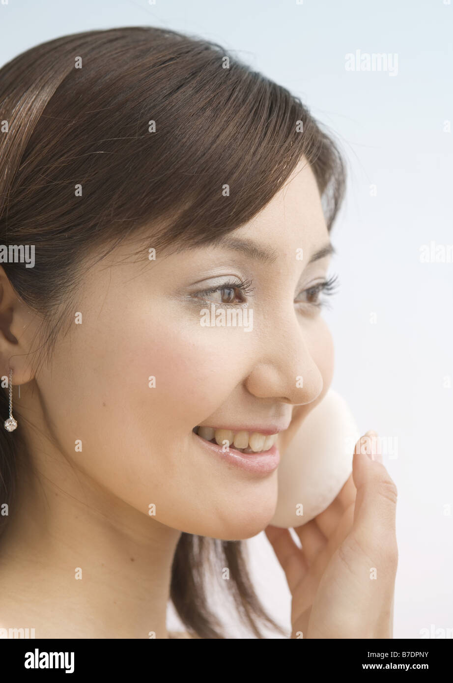 Woman applying powder with puff Stock Photo - Alamy