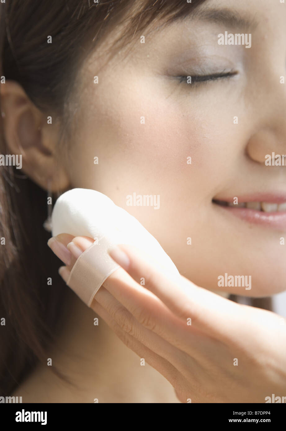 Woman applying powder with puff Stock Photo - Alamy