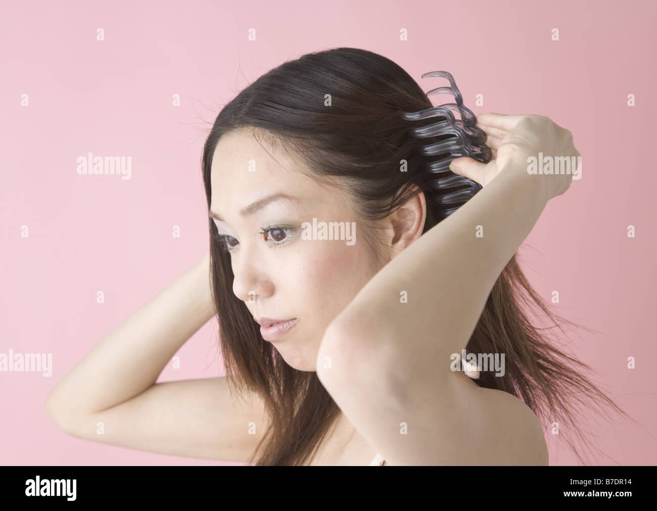 Young woman styling hair back Stock Photo - Alamy