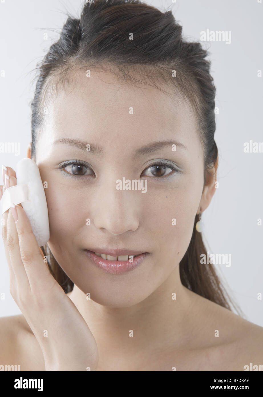 Woman applying powder with puff Stock Photo - Alamy