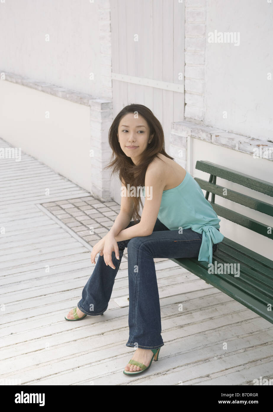 Young woman sitting on bench Stock Photo - Alamy