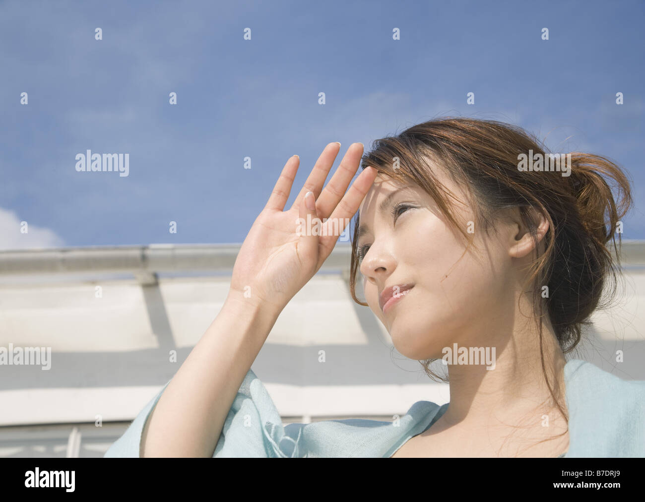 Woman shielding eyes from sun Stock Photo - Alamy