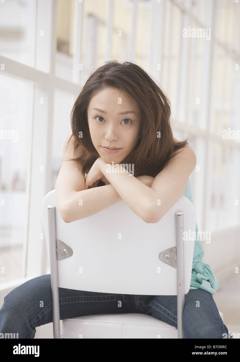 Young woman leaning on back of chair Stock Photo - Alamy