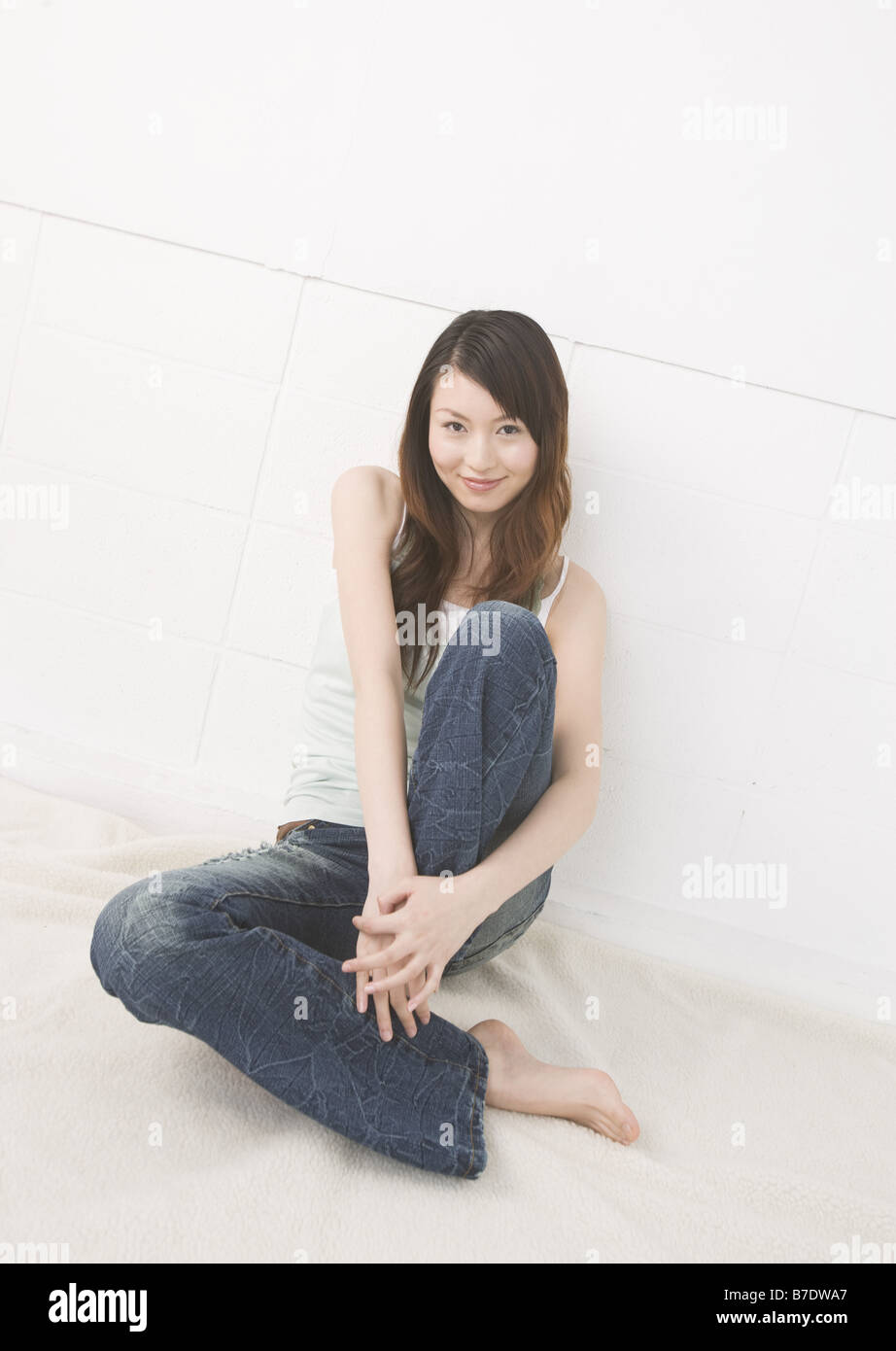 Woman sitting on floor with arms around knee Stock Photo - Alamy