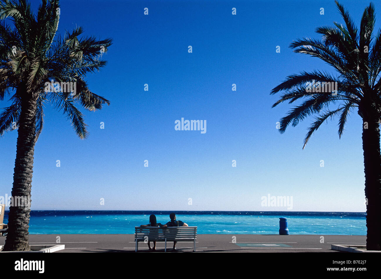 A couple seating on a bench faces to the sea on the Promenade des ...