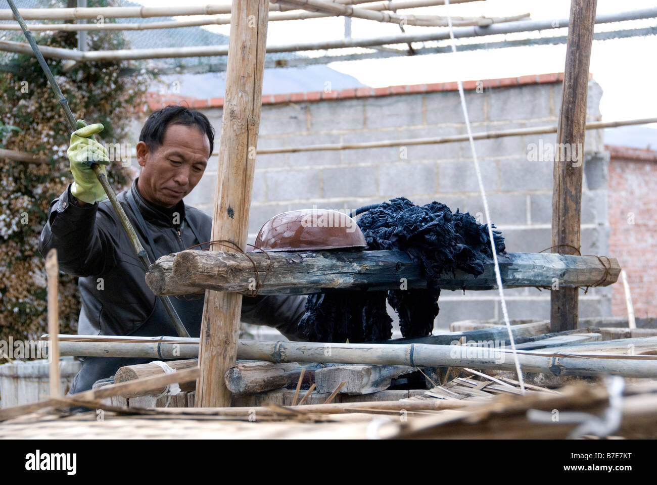 Worker stirs a large vat of blue dye to colour the traditional tie-dyed ...