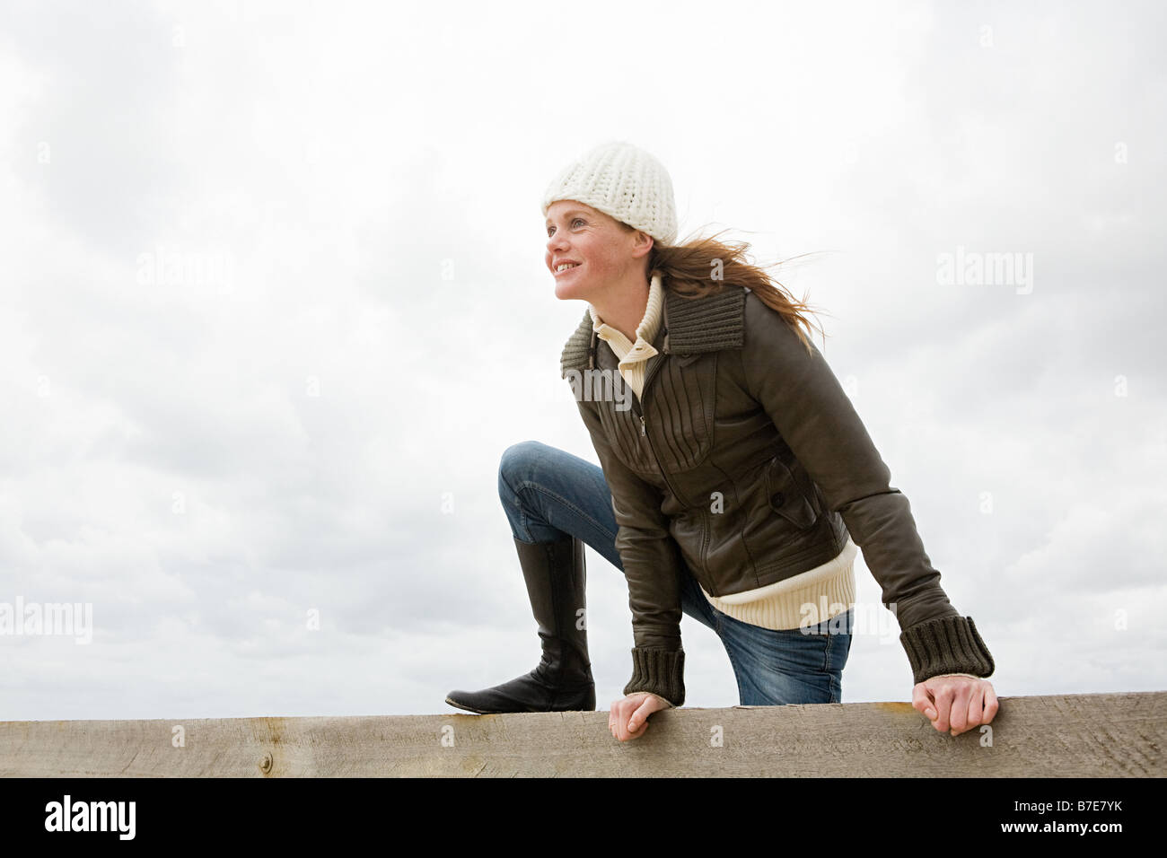 Woman climbing over wall Stock Photo - Alamy