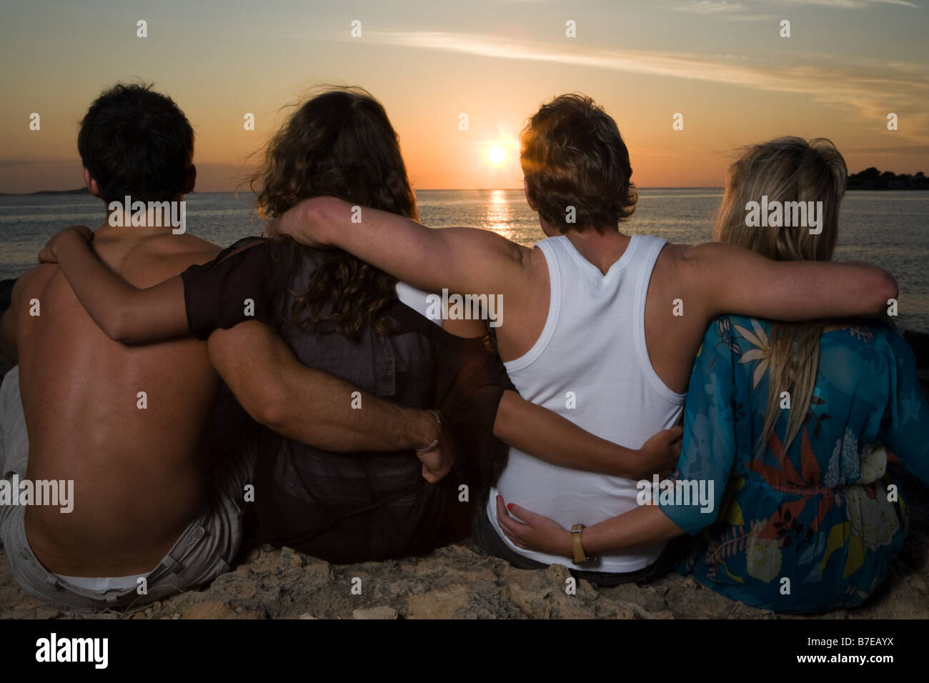 Friends watching the sunset by sea Stock Photo - Alamy