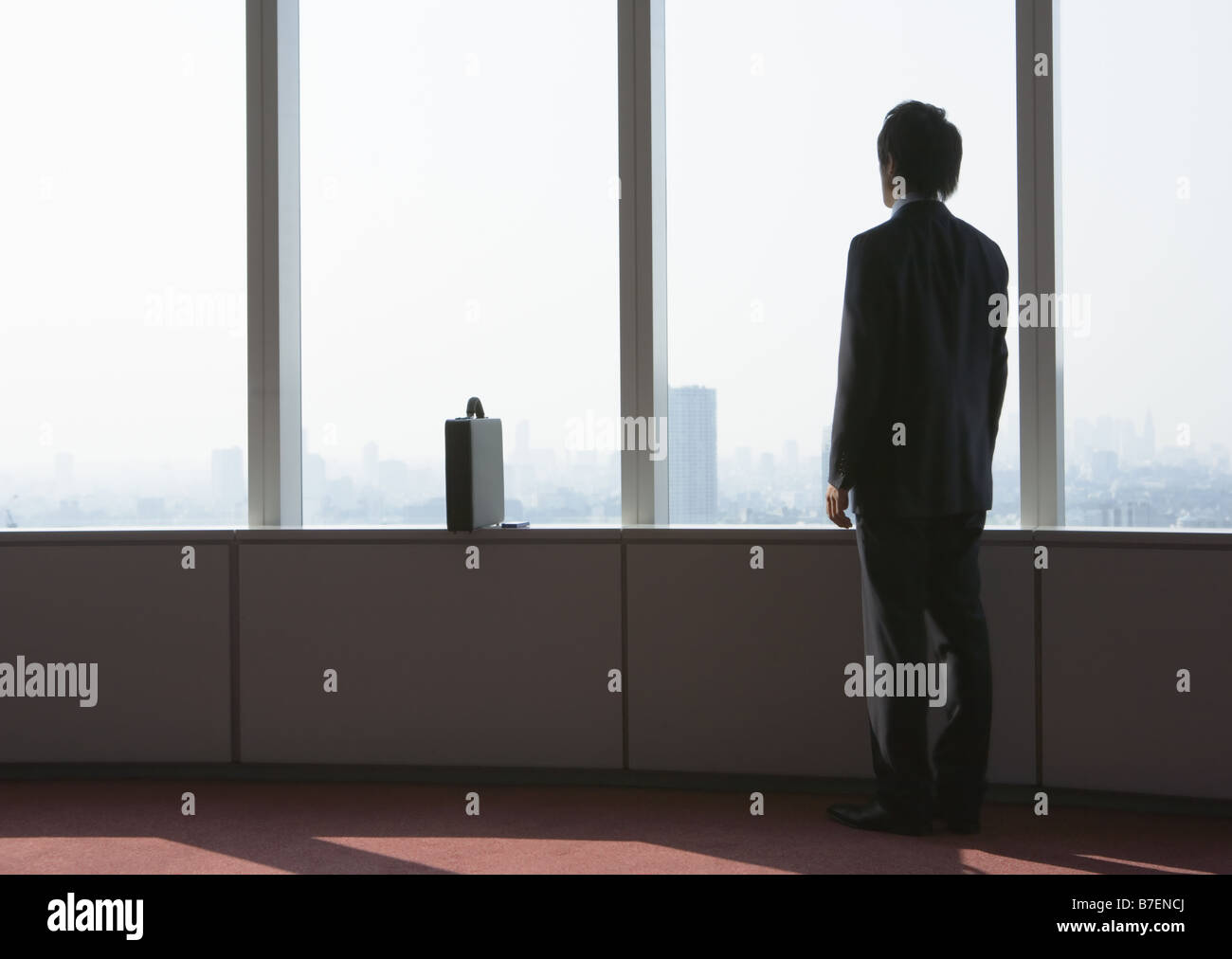 Businessman standing window looking distance hi-res stock photography ...