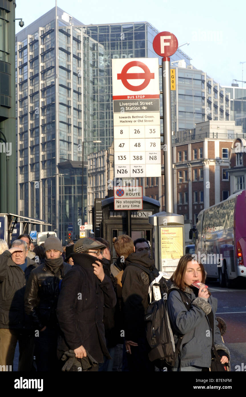 Commuters wait at a bus stop on a cold day in Winter near Liverpool ...
