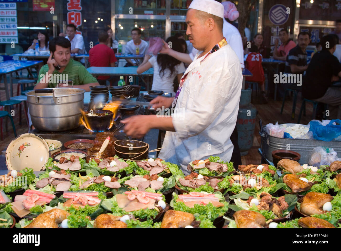 A man cooking up dishes at a stall at the night food market in Urumqi ...