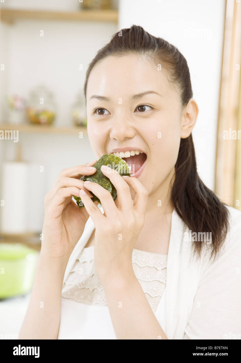A woman eating rice ball Stock Photo - Alamy