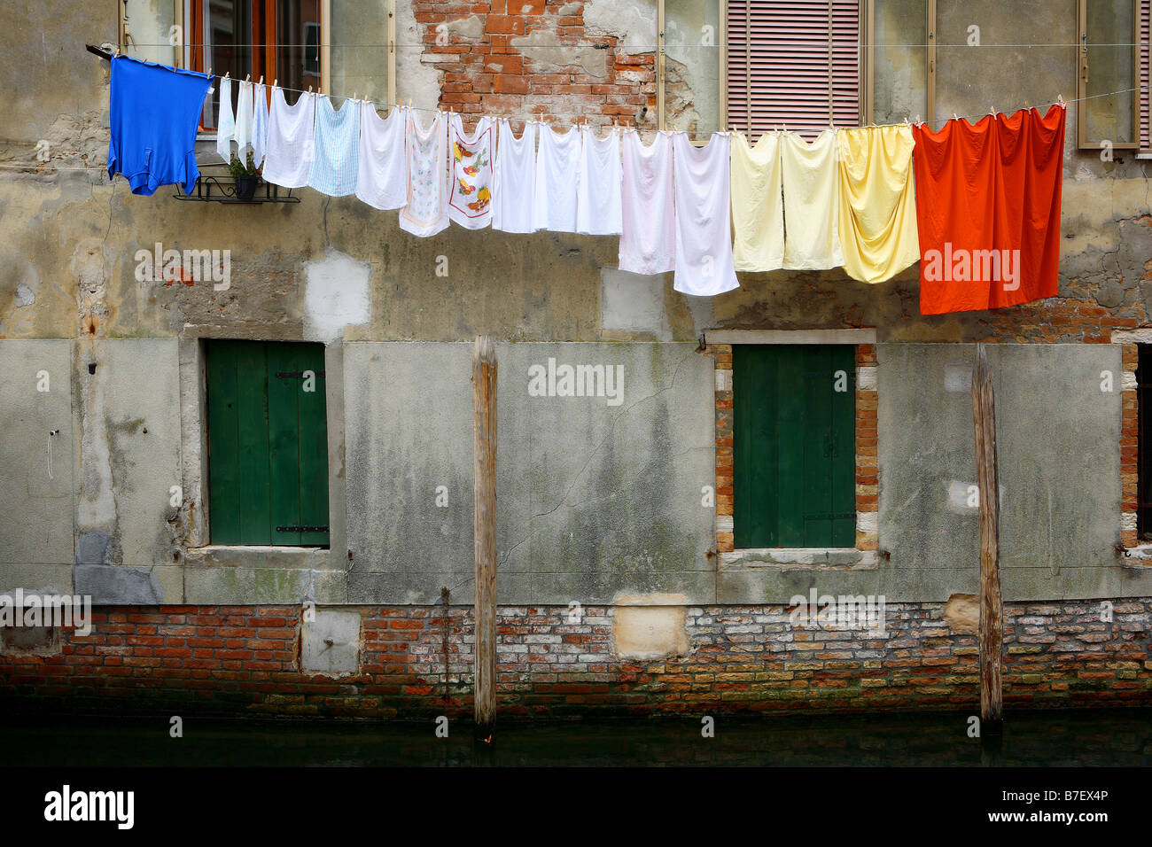 rainbow of colorful clothes hanging on clothes line along side building ...