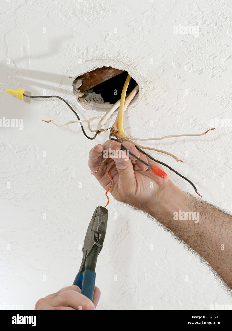 A closeup of an electrician s hands as he uses pliers to straighten ...