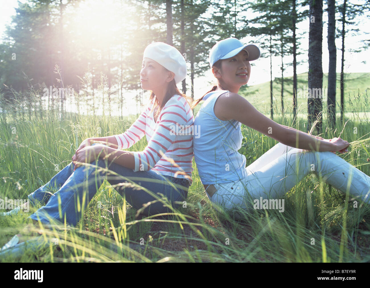Women sitting back-to-back Stock Photo - Alamy