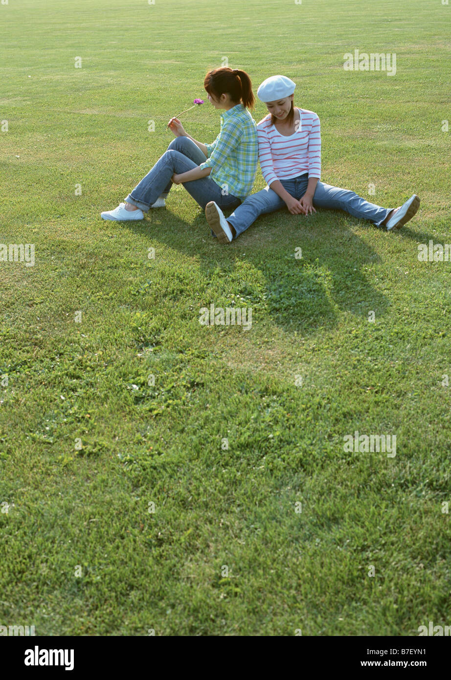 Women sitting back-to-back Stock Photo - Alamy