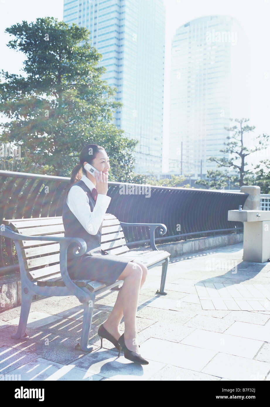 Business woman on cell-phone on bench Stock Photo - Alamy