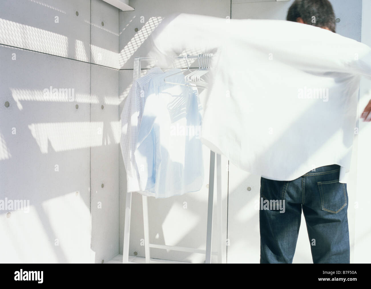 Man putting on shirt Stock Photo - Alamy