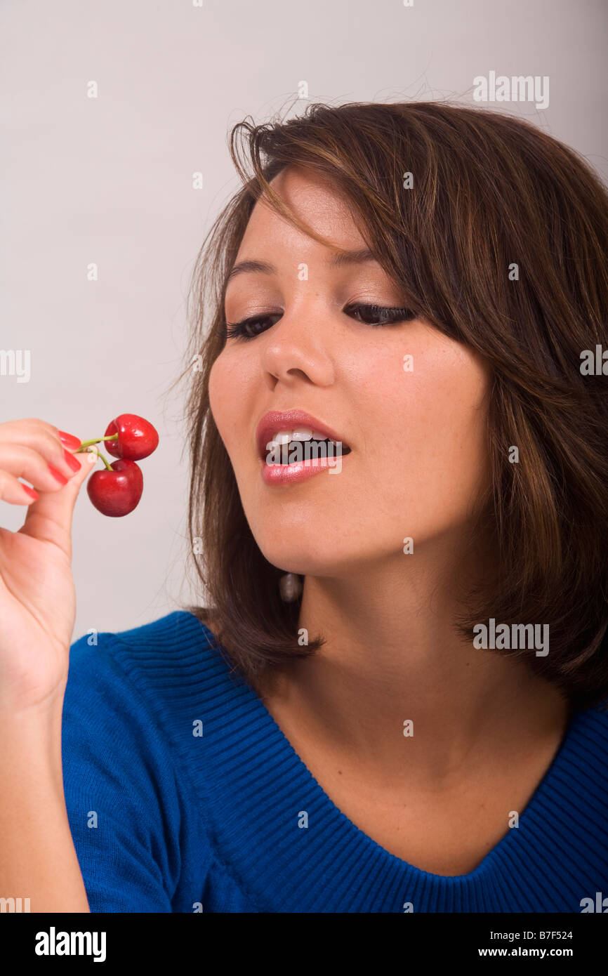A beautiful young Asian-American girl eating red cherries Stock Photo ...