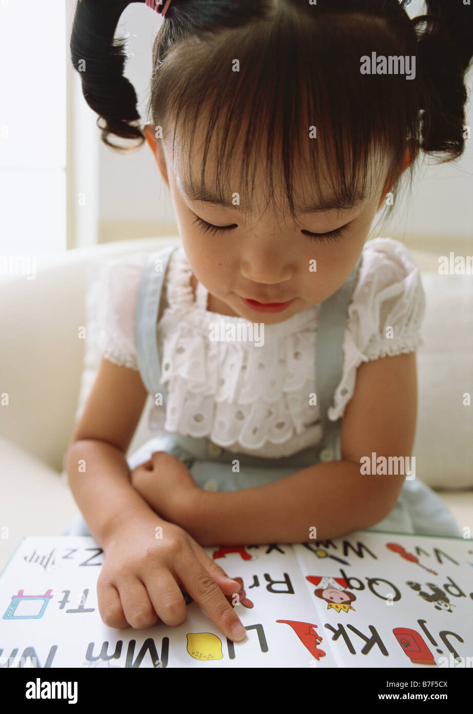 Girl reading picture book Stock Photo - Alamy