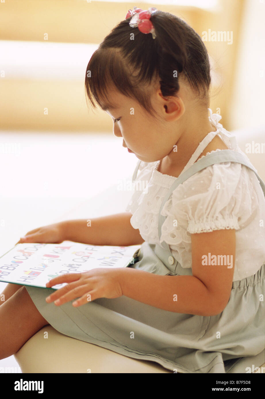 Girl reading picture book Stock Photo - Alamy