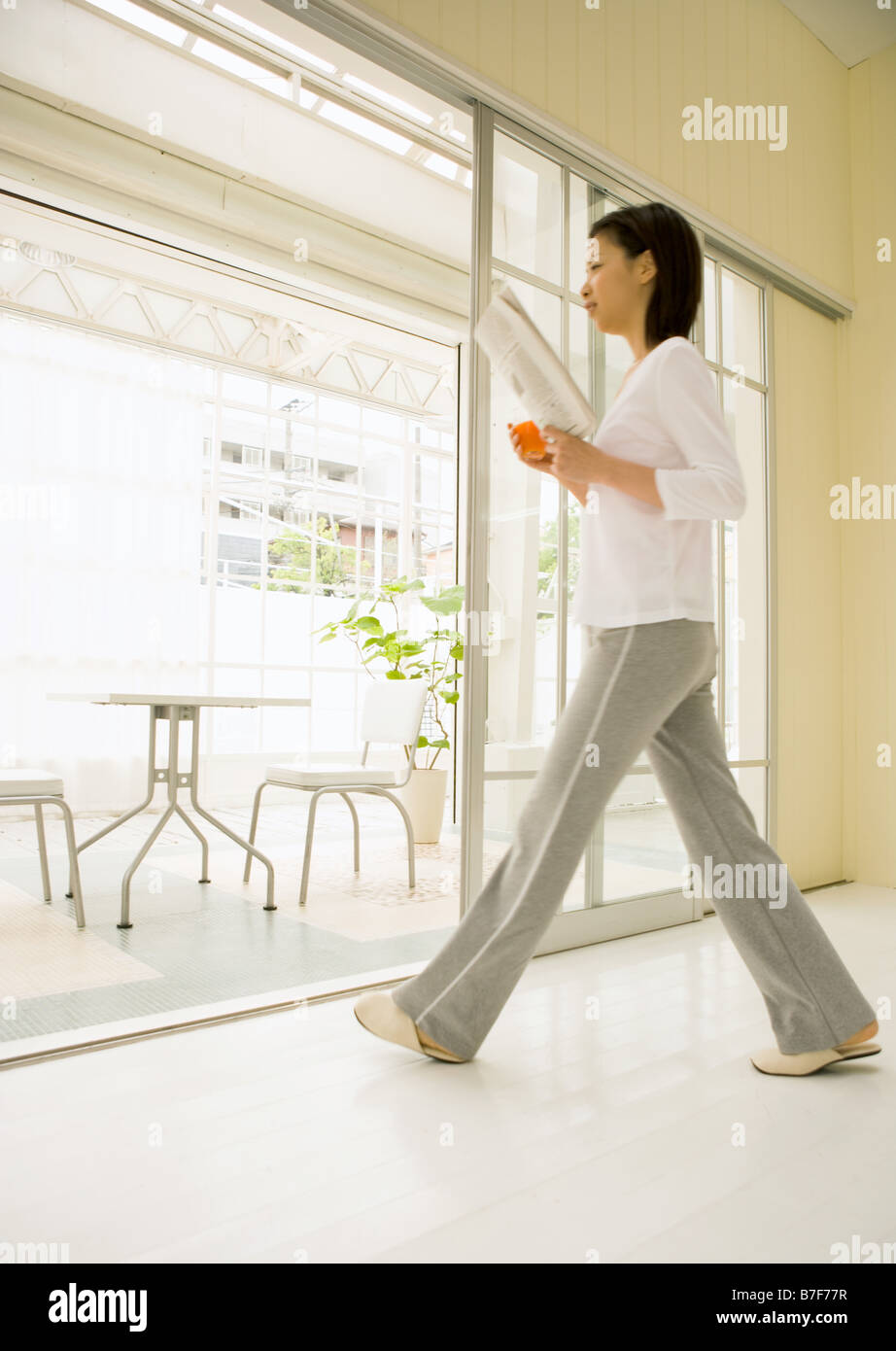 Woman walking with reading newspaper Stock Photo - Alamy