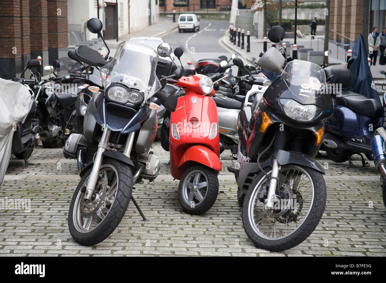 Line of bikes on a paved city street with a small red scooter in the ...