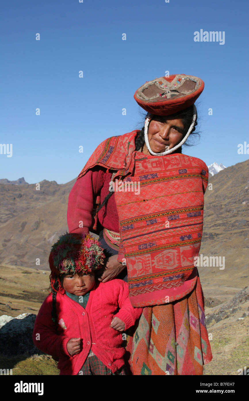 Old woman in traditional Peruvian dress and hat standing with child ...