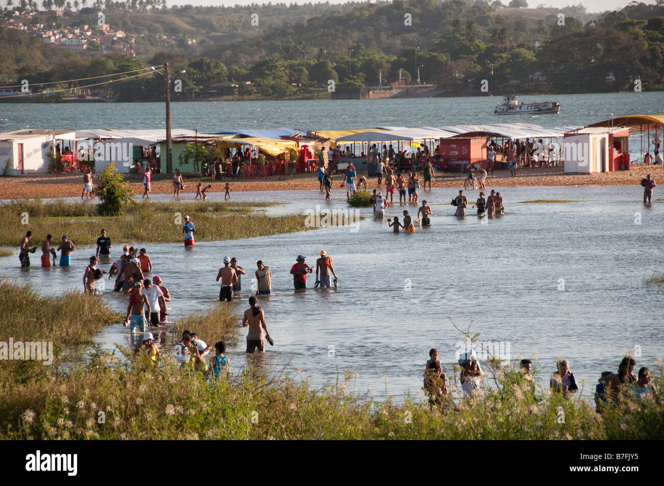 People walk through water to reach a river beach with a small number of ...